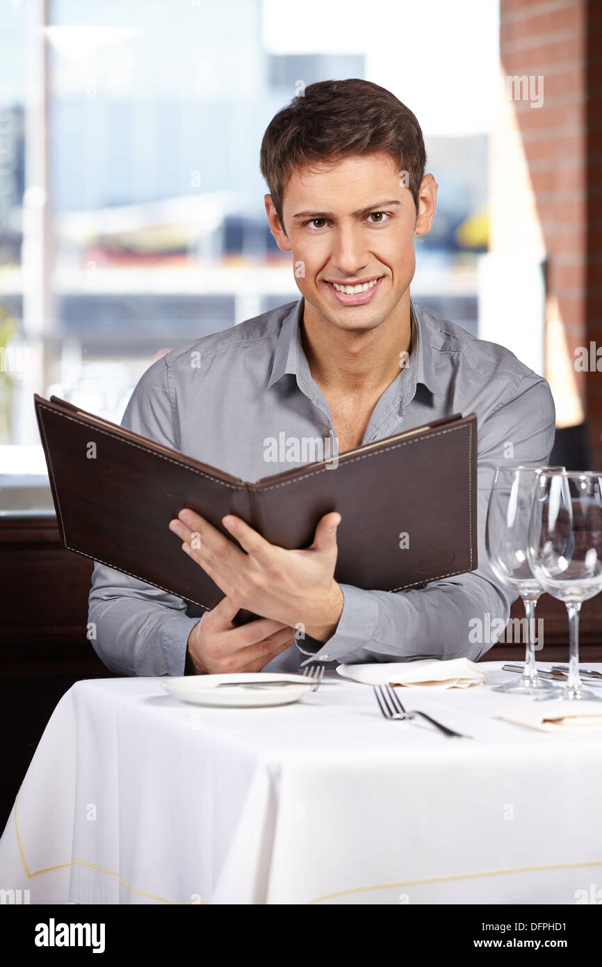 Smiling attractive man reading the menu at a restaurant Stock Photo - Alamy