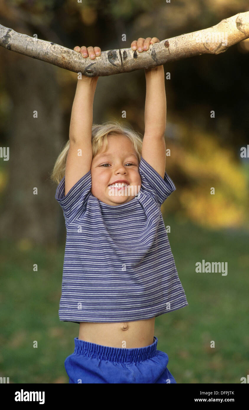 Boy hanging from tree branch hi-res stock photography and images - Alamy