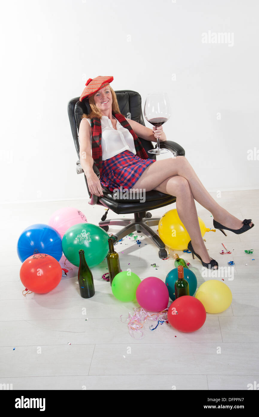 Party goer wearing a kilt and drinking red wine from a large glass ...
