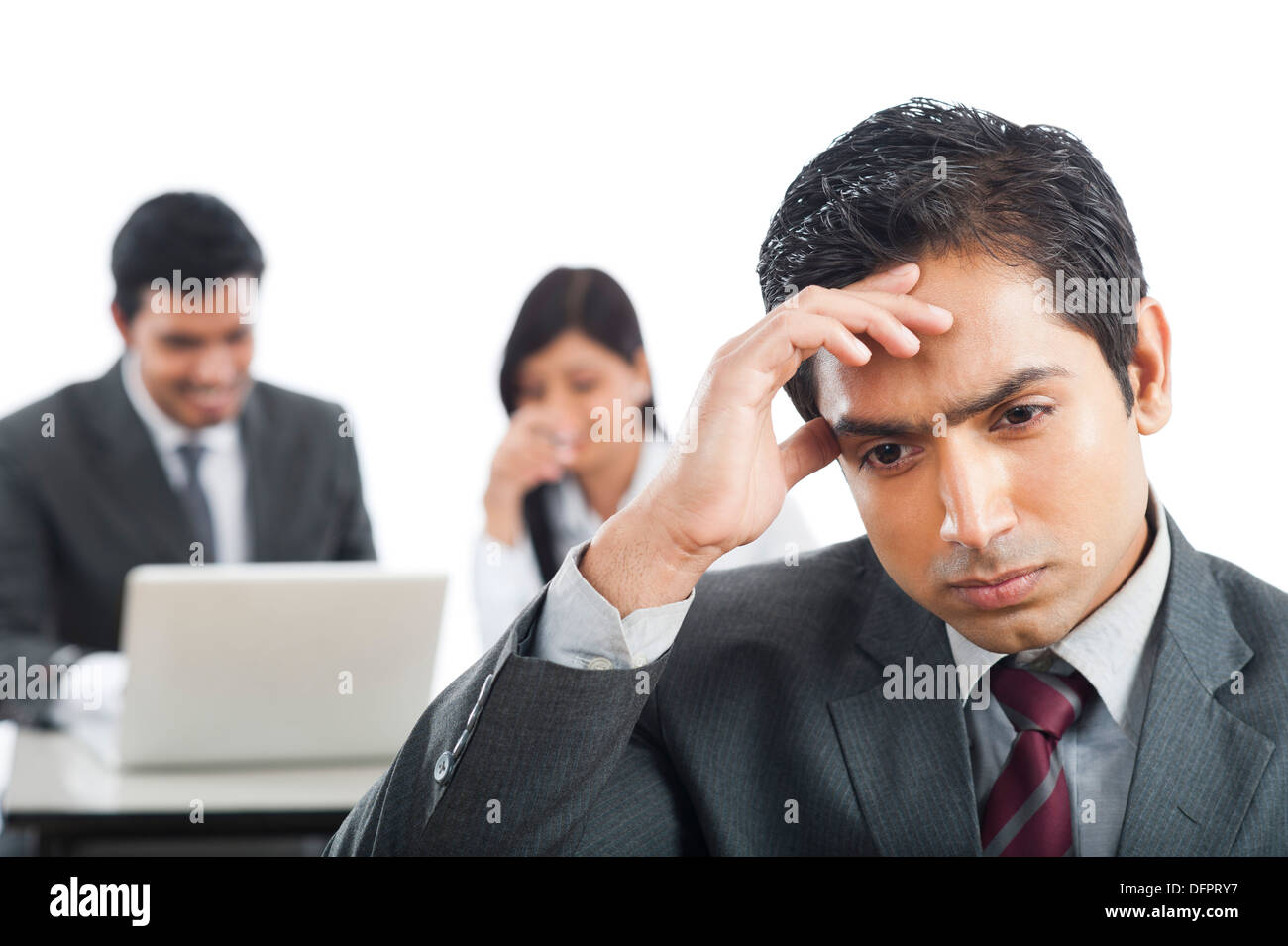 Close-up of a businessman looking upset with his colleagues in the ...