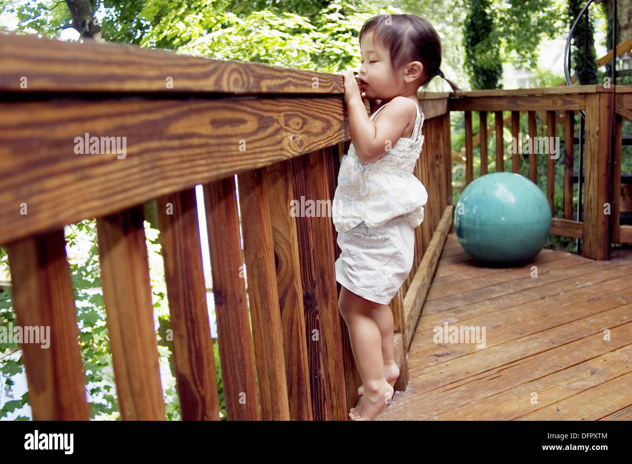 2-year-old Vietnamese girl looking over the railing of a deck Stock ...
