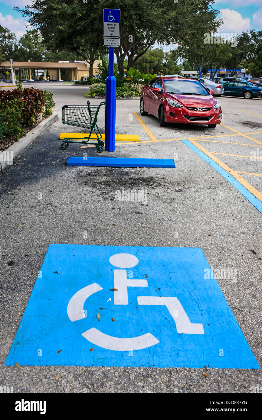 Blue and white handicapped sign painted on the asphalt in a plaza car ...