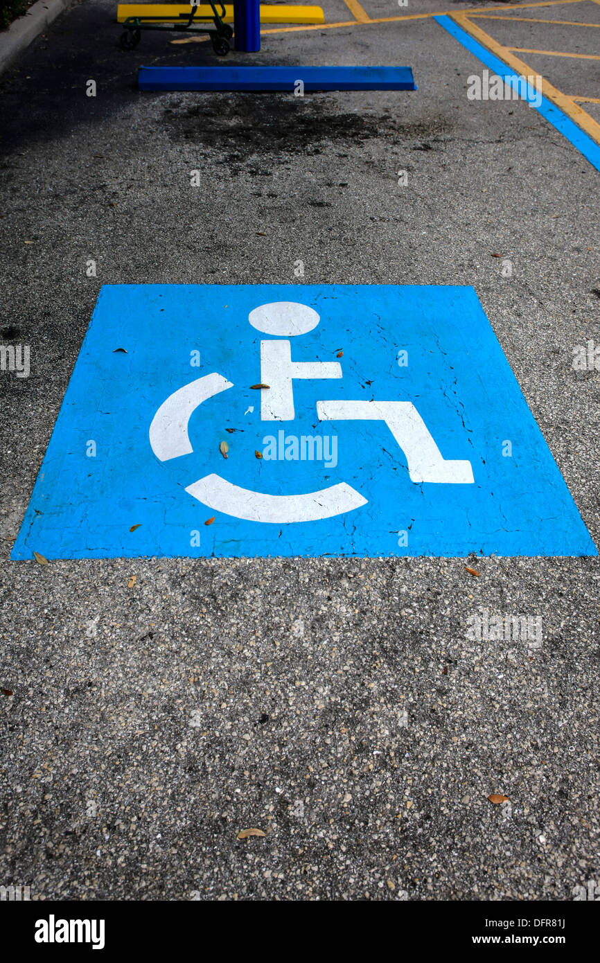 Blue and white handicapped sign painted on the asphalt in a plaza car ...