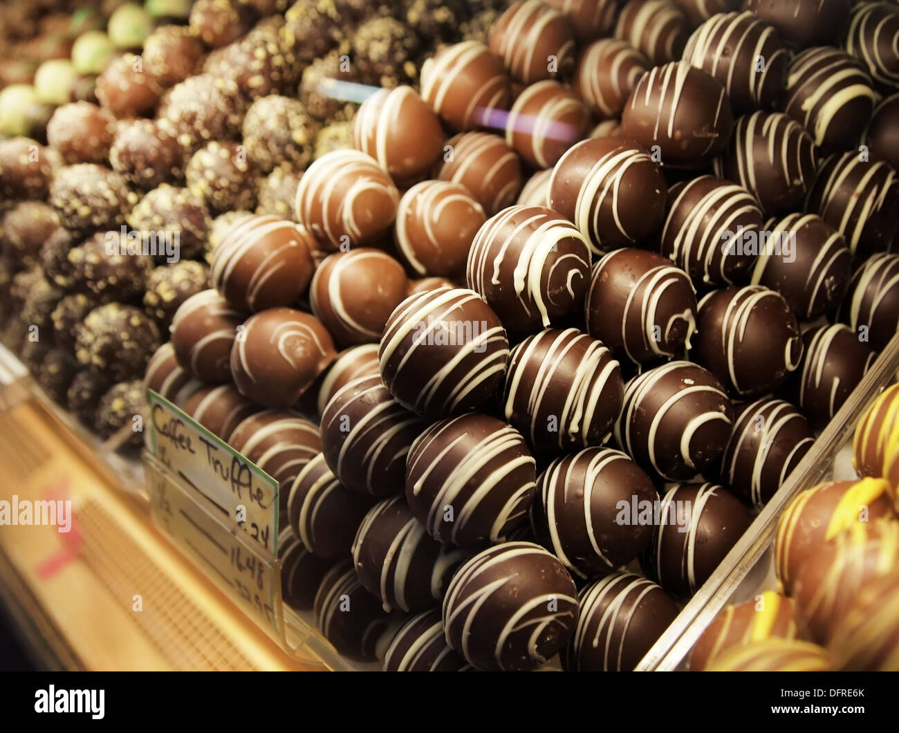 An assortment of chocolate truffle candies in a glass display case at a ...