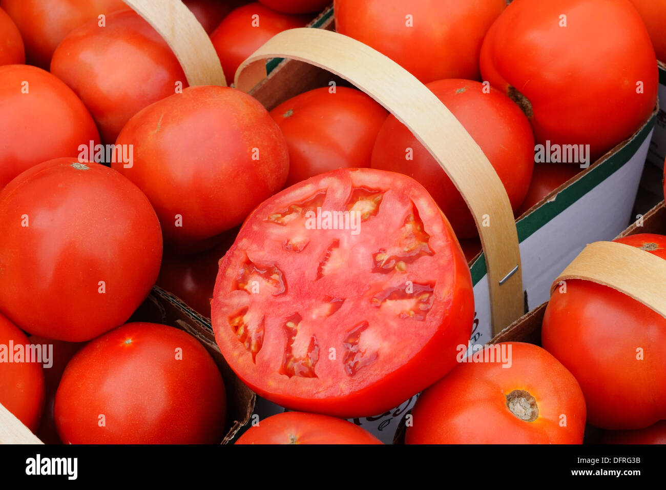A cut tomato sample on ripe tomatoes in boxes at a Canadian market ...