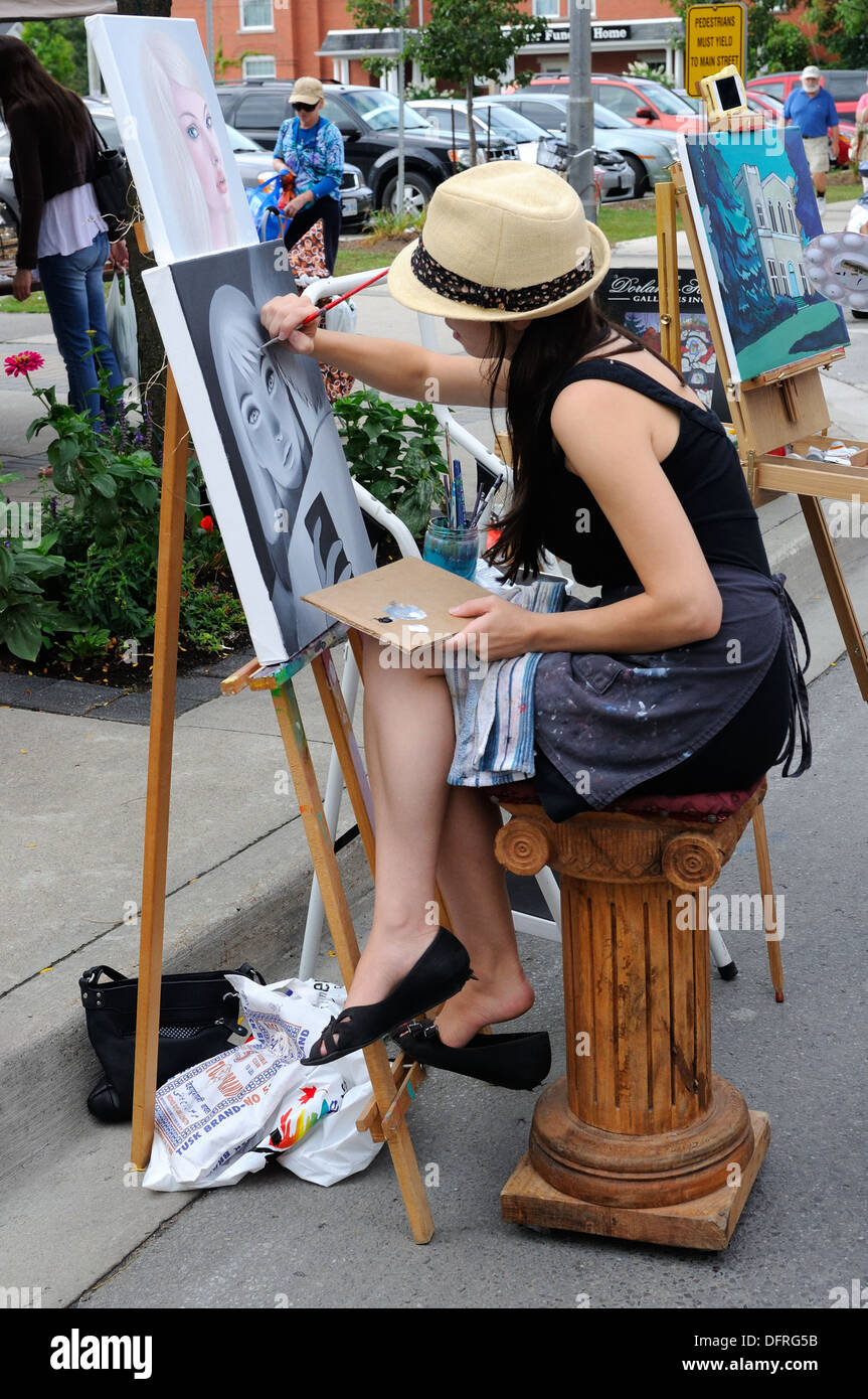 Young lady artist painting a canvas on a street at the Milton farmers ...