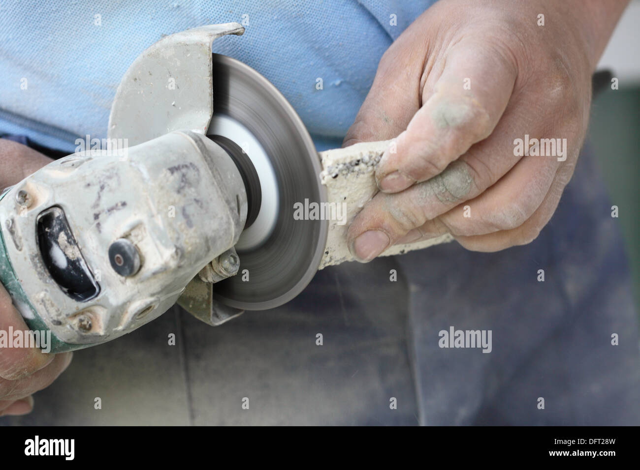 Renovation at home worker cuts tile with angle grinder electric tool ...