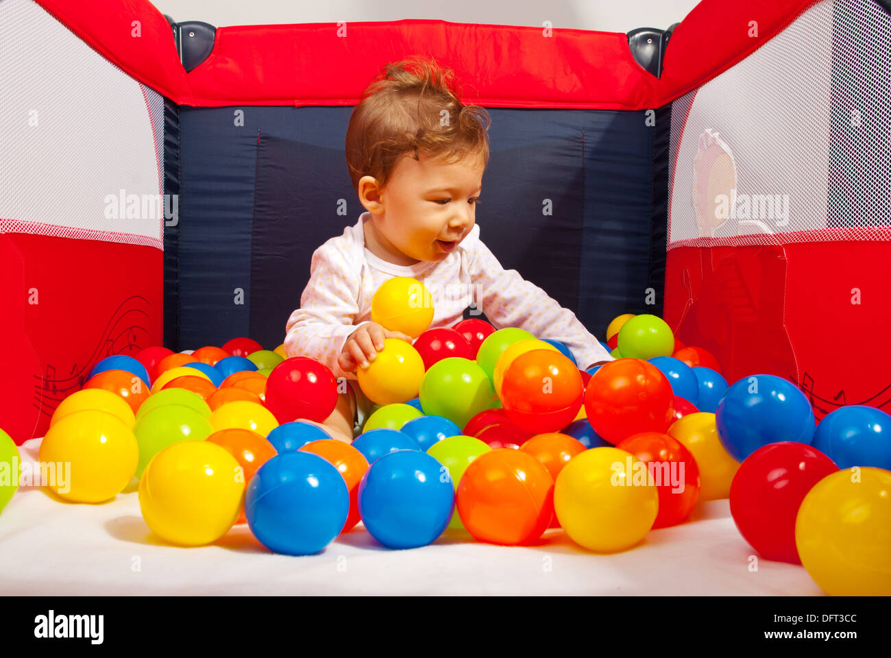 Baby boy playing with colorful balls inside playpen Stock Photo - Alamy
