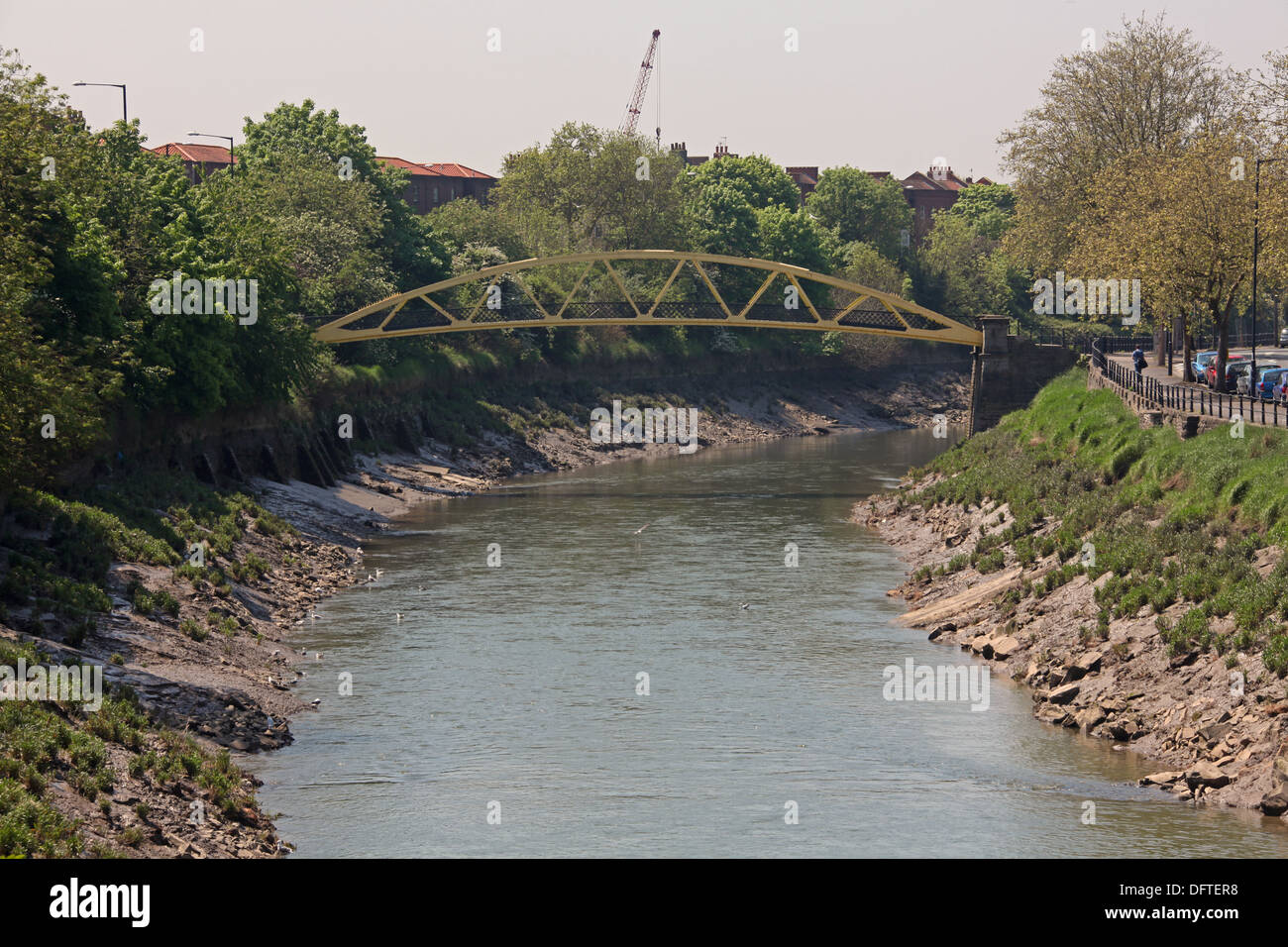 A long distance picture of a foot bridge spanning a tidal waterway with ...