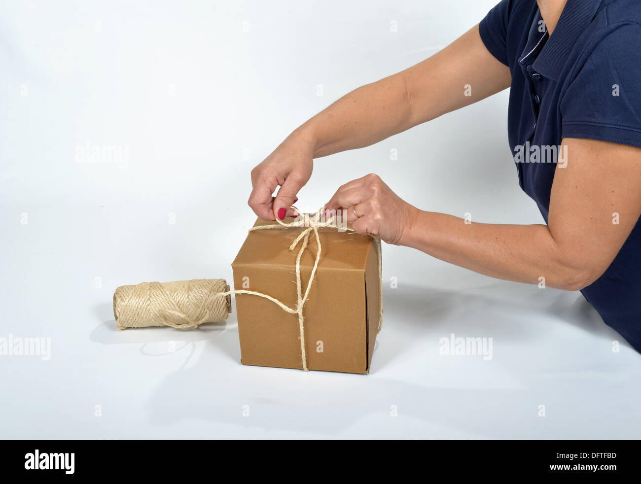 Cardboard packing a young woman with a spool of string Stock Photo - Alamy