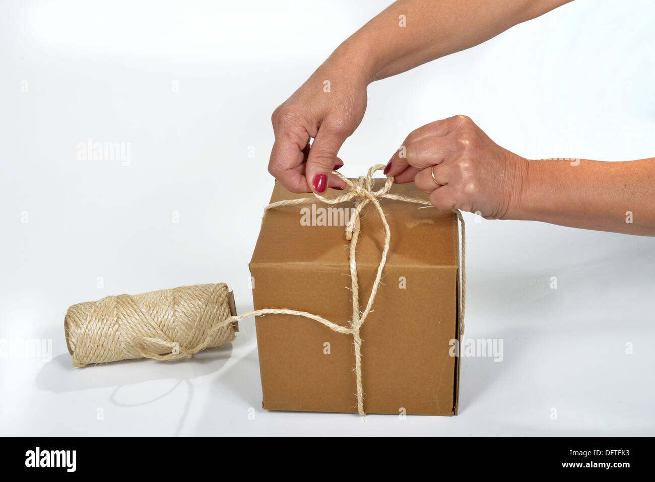 Cardboard packing a young woman with a spool of string Stock Photo - Alamy