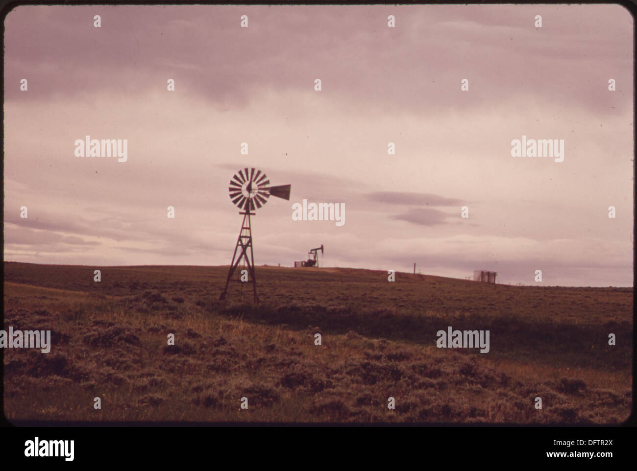 A windmill stands in the river near the rolling ranch lands close to ...