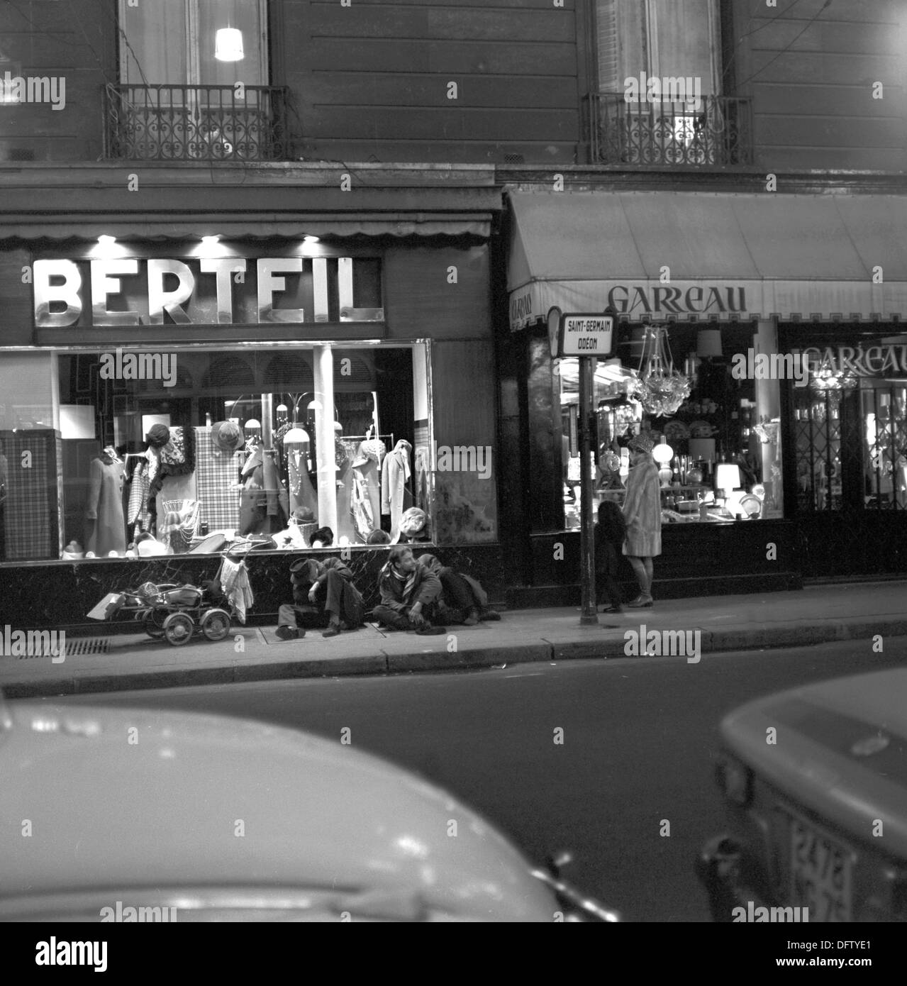 Three homeless people beg in front of a high class fashion store while ...
