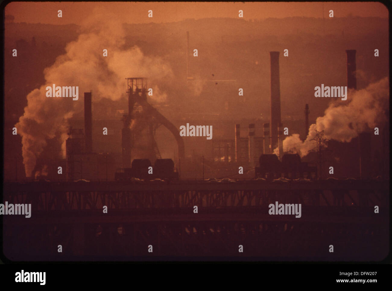 This photograph captures a sunrise scene with smoke rising from a steel ...