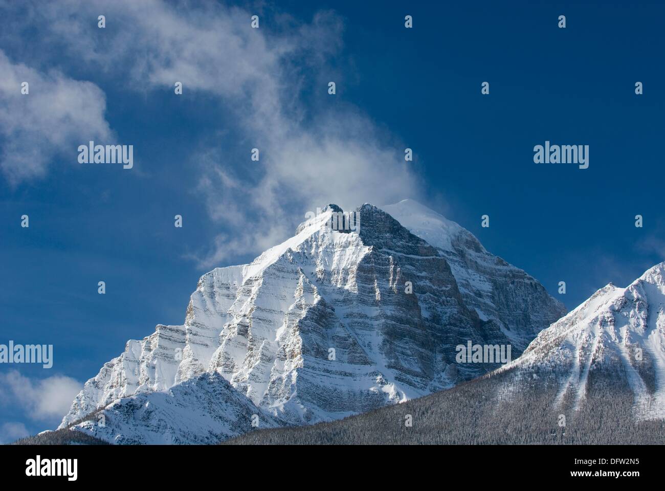 Clouds and snow blowing off the summit of Mount Temple on a cold winter ...