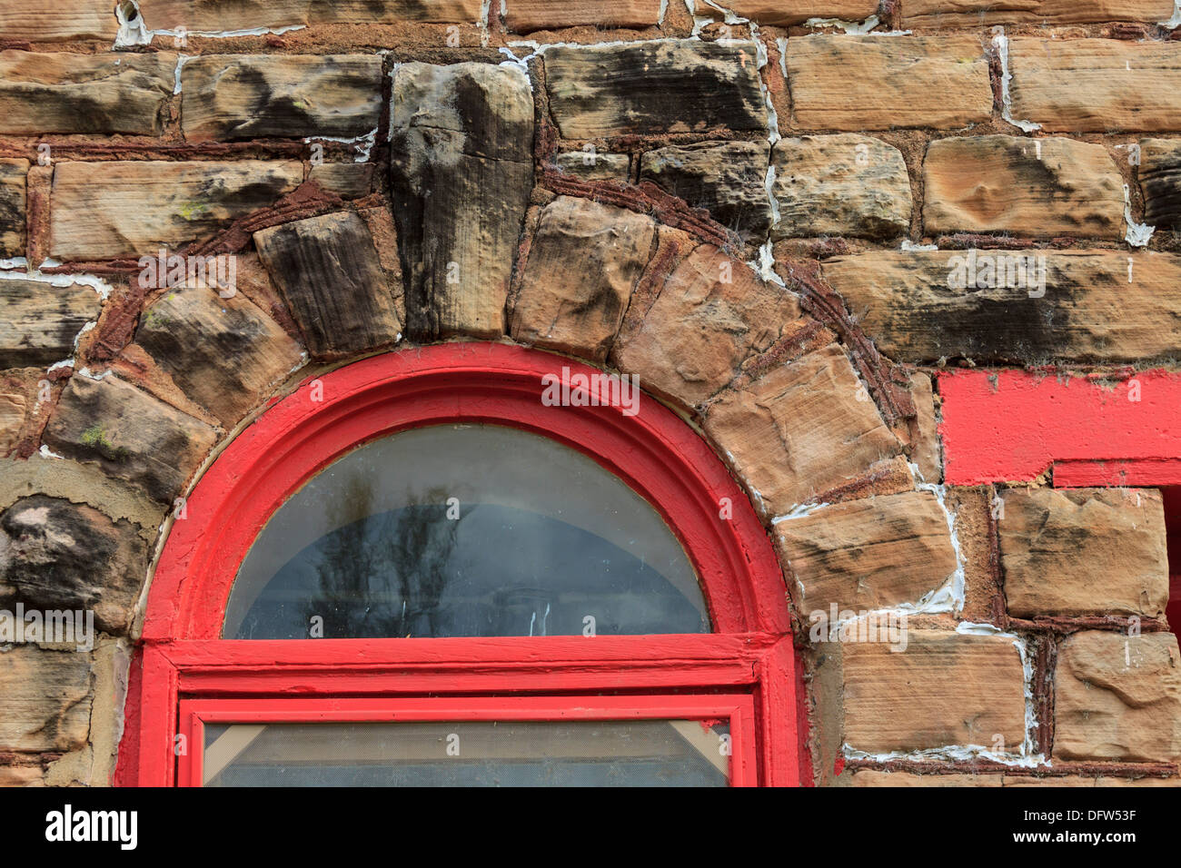 A bright red window arch in an old sandstone building Stock Photo - Alamy