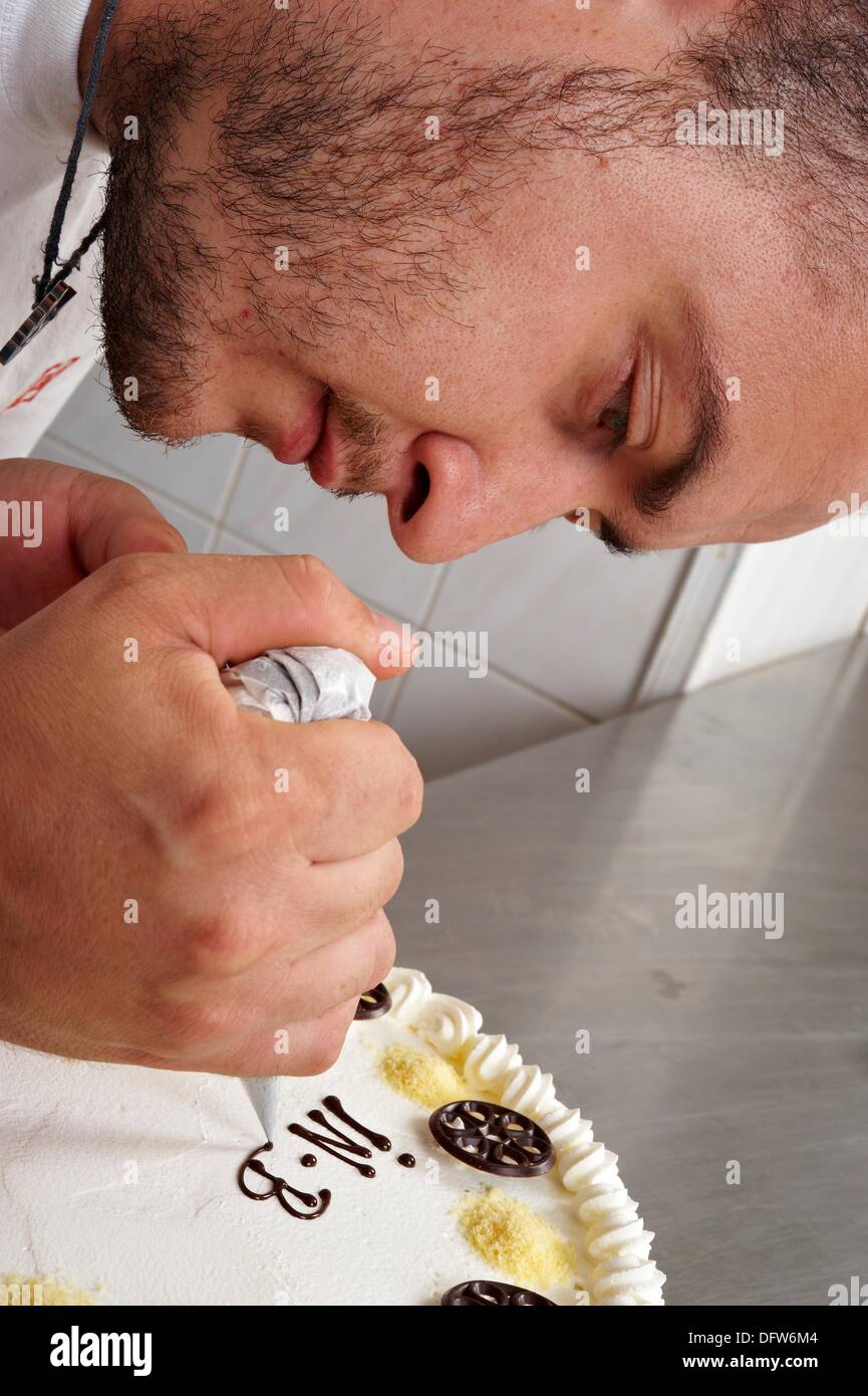 A pastry chef decorating a cake with chocolate cream Stock Photo - Alamy