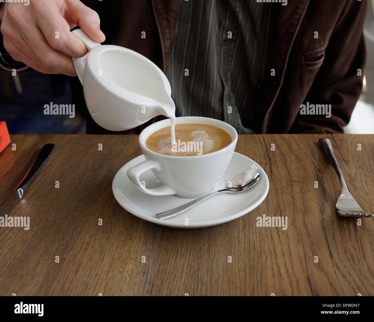 Man pouring milk into coffee Stock Photo - Alamy