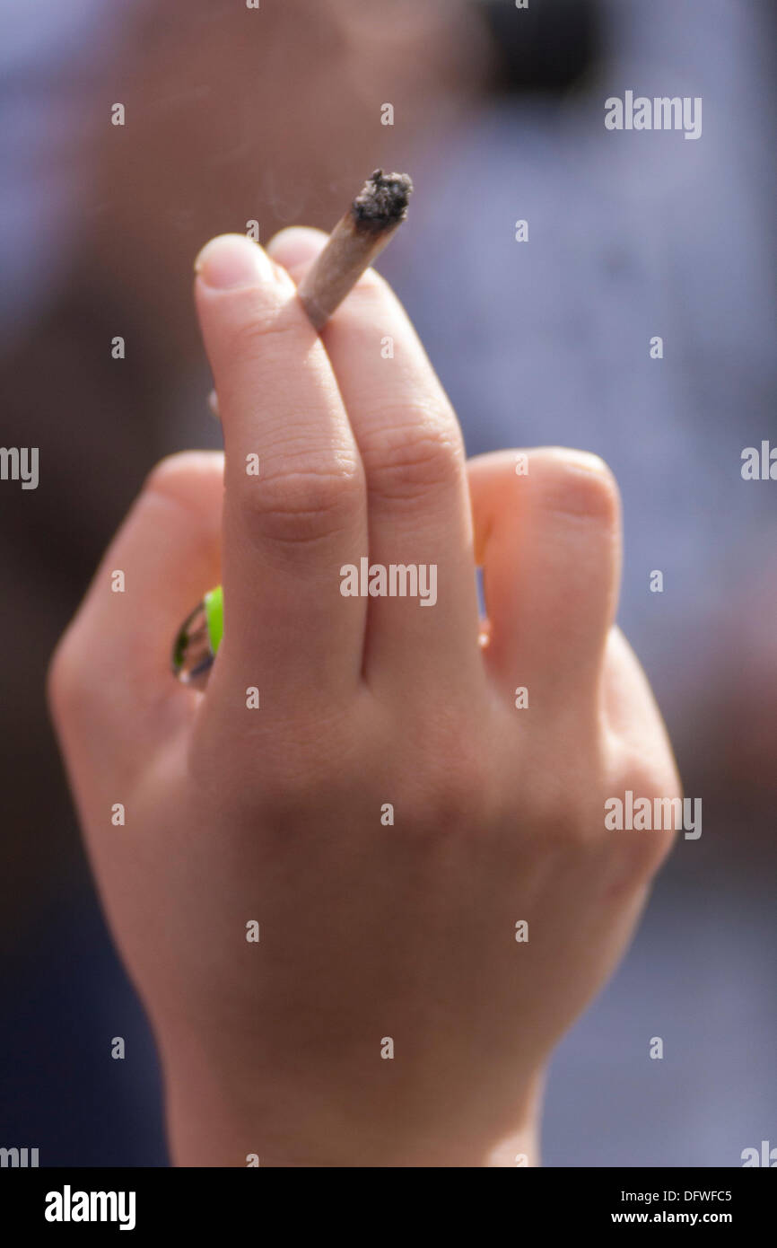 London, UK. 09th Oct, 2013. A hand holds up a smouldering joint as ...