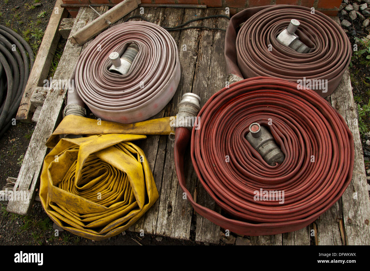 Old industrial water hoses neatly rolled on a wooden pallet ready for ...
