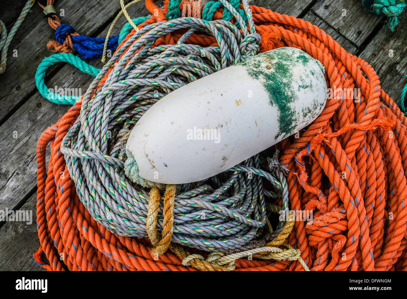 A white float sits on top of coiled ropes on a dock at the harbor at ...