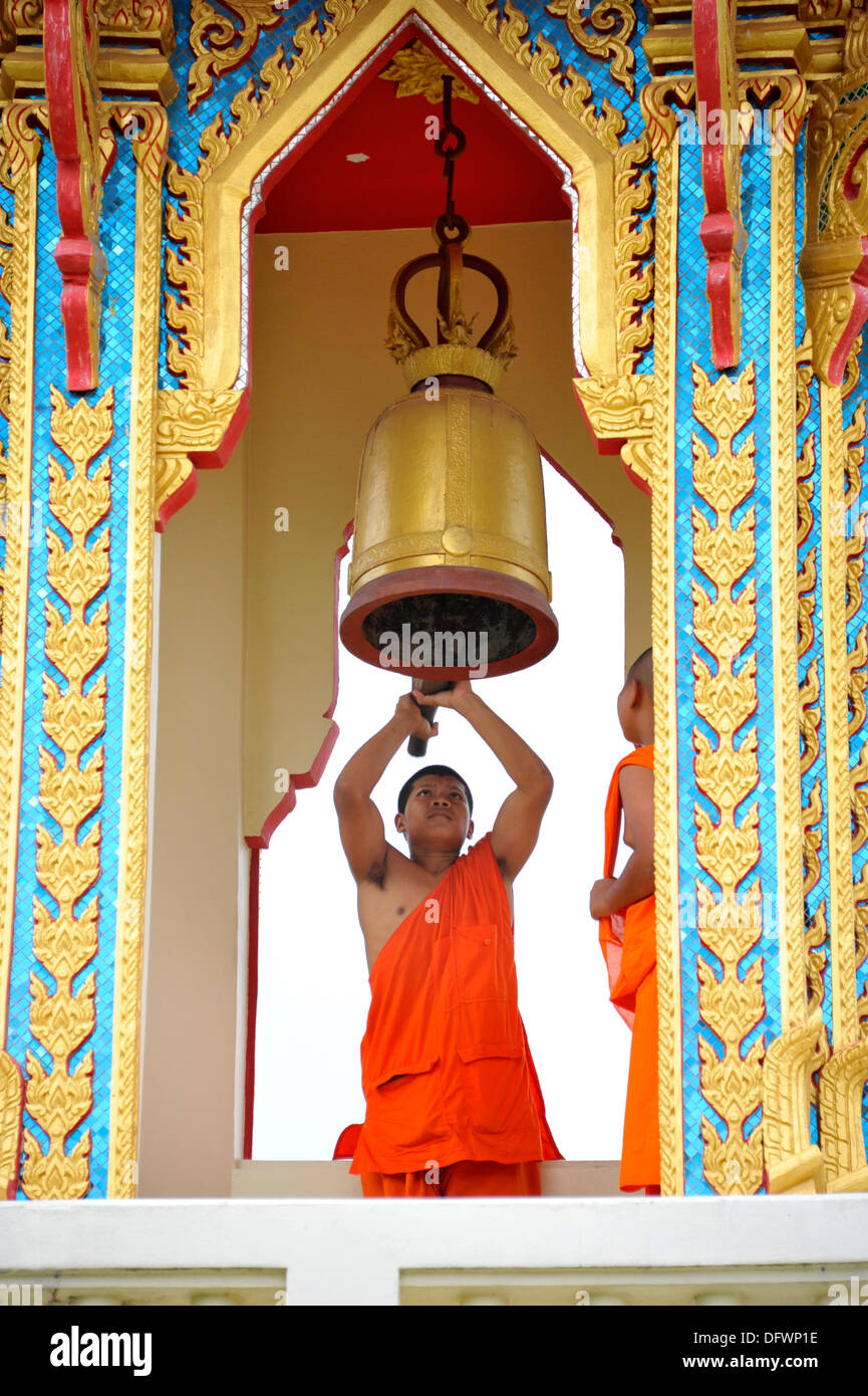 Thai buddhist monk striking a bell at temple Wat Thong Kung, beside the ...