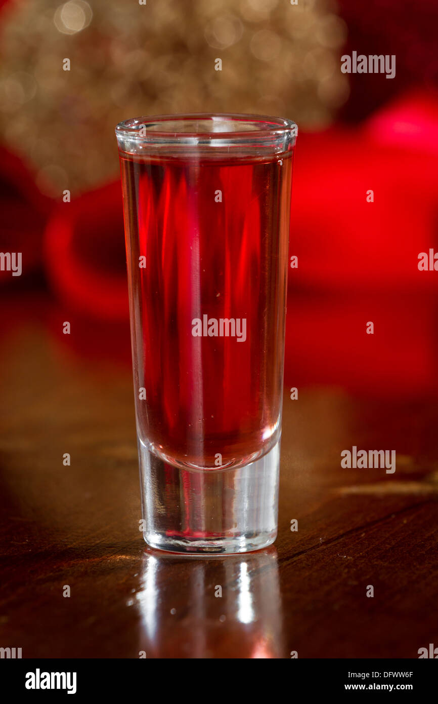 red holiday shot served in a clear tall glass with an out of focus ...