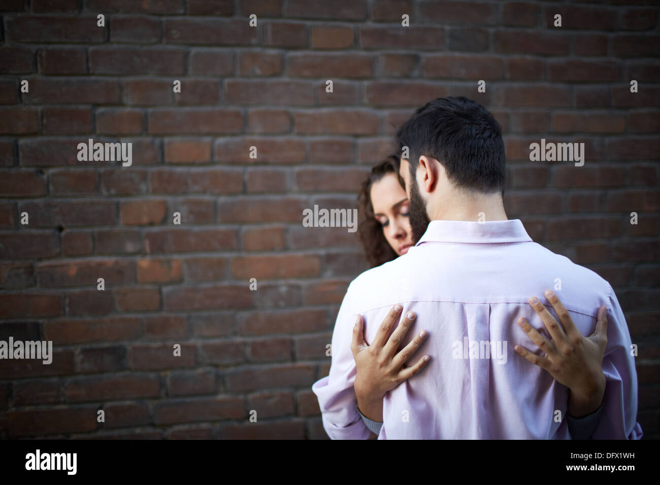 Rear view of young man being embraced by his girlfriend Stock Photo - Alamy