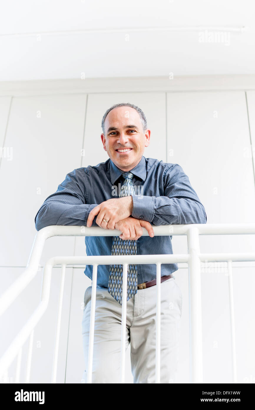 Smiling proud business man standing in office hallway leaning on ... Smiling proud business man standing in office hallway leaning on ...