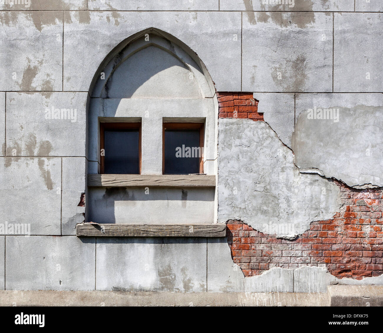Arched window, concrete wall, peeling plaster and exposed brinks of a ...