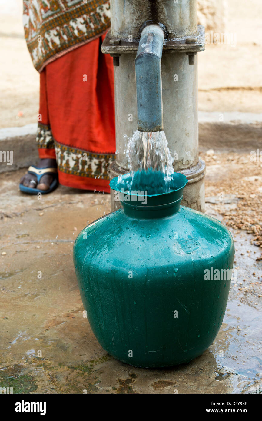 Rural indian woman filling plastic water pot from a rural water pump ...