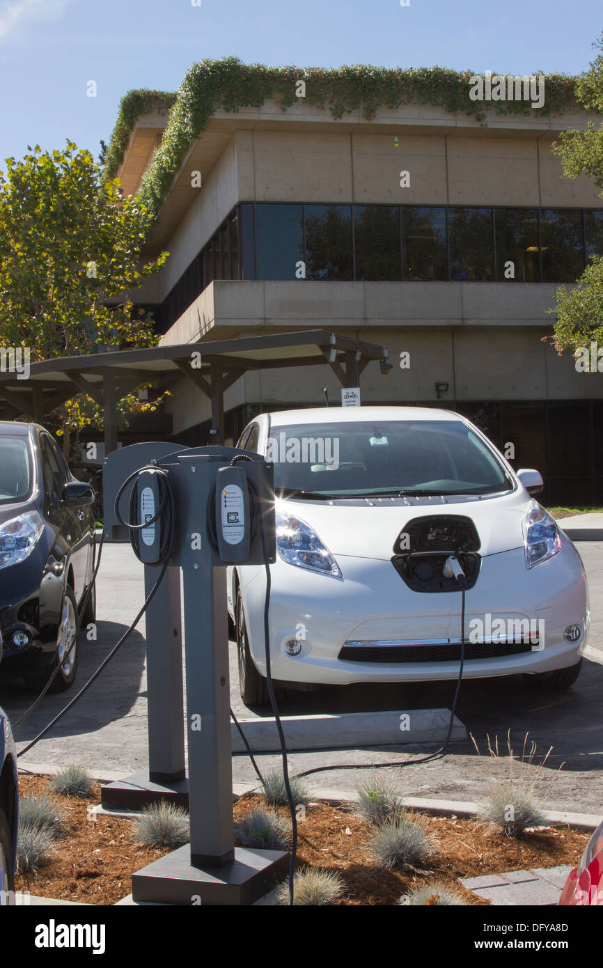 Plug-in electric cars plugged into an EV charging station to charge ...