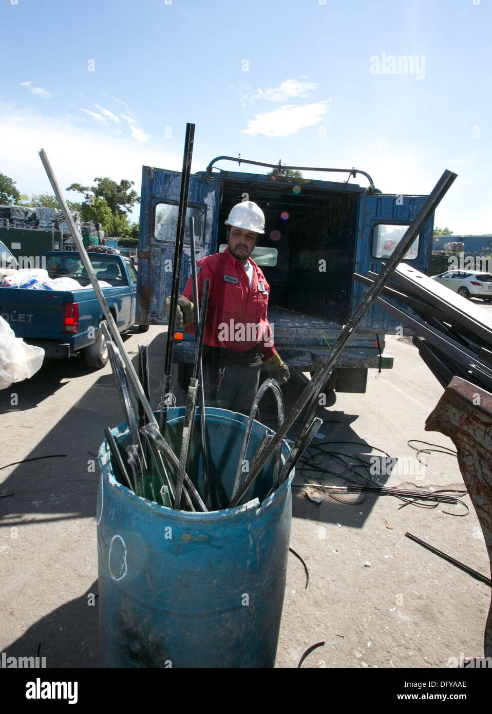 Hispanic male worker arranges metal inside plastic tub for recycling at ...