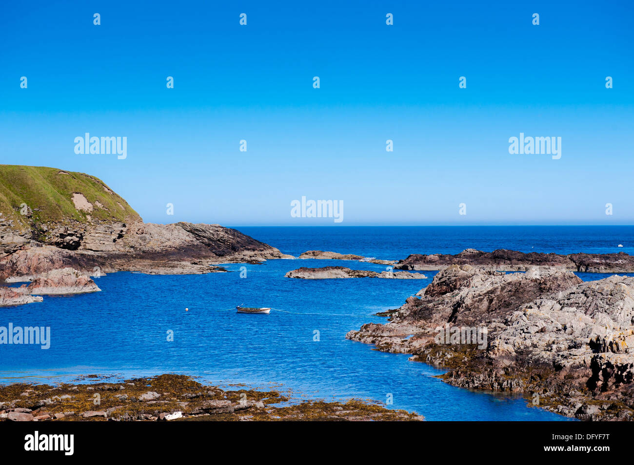 Rocky inlet with small fishing boat Stock Photo - Alamy