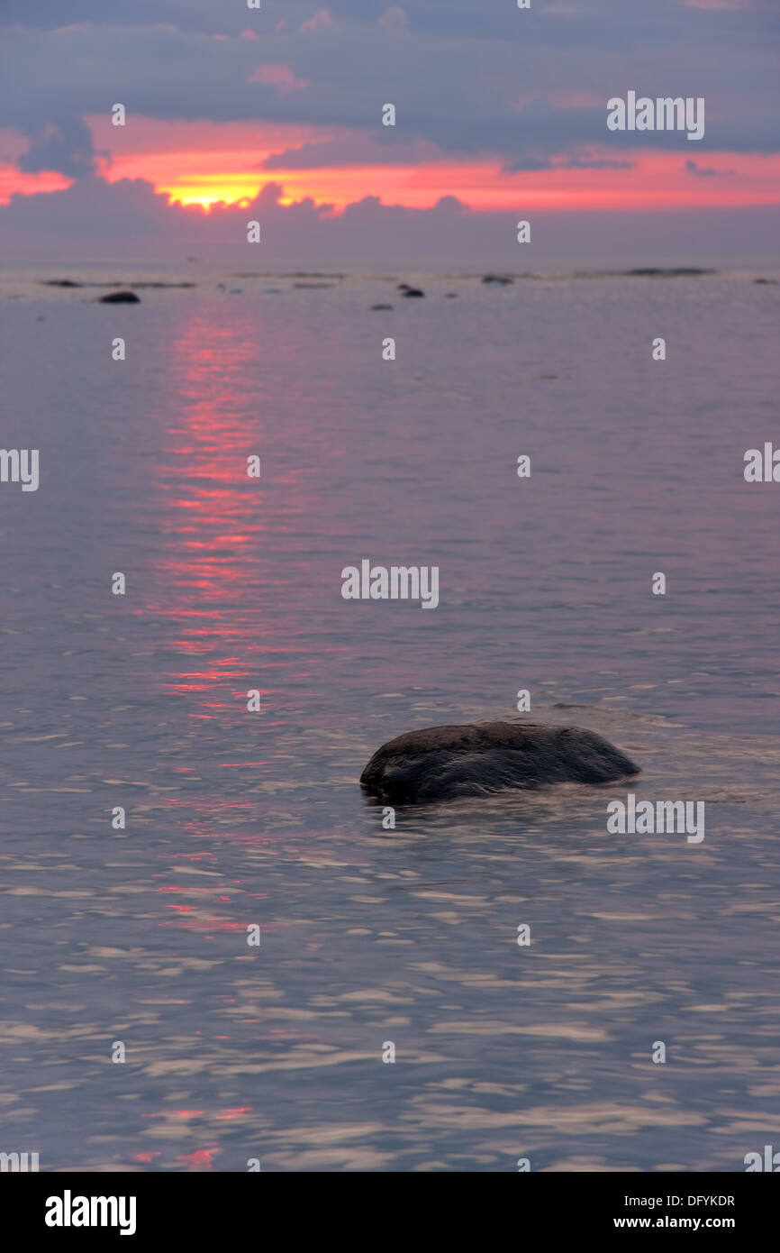 Stone in sea at sunset Stock Photo - Alamy