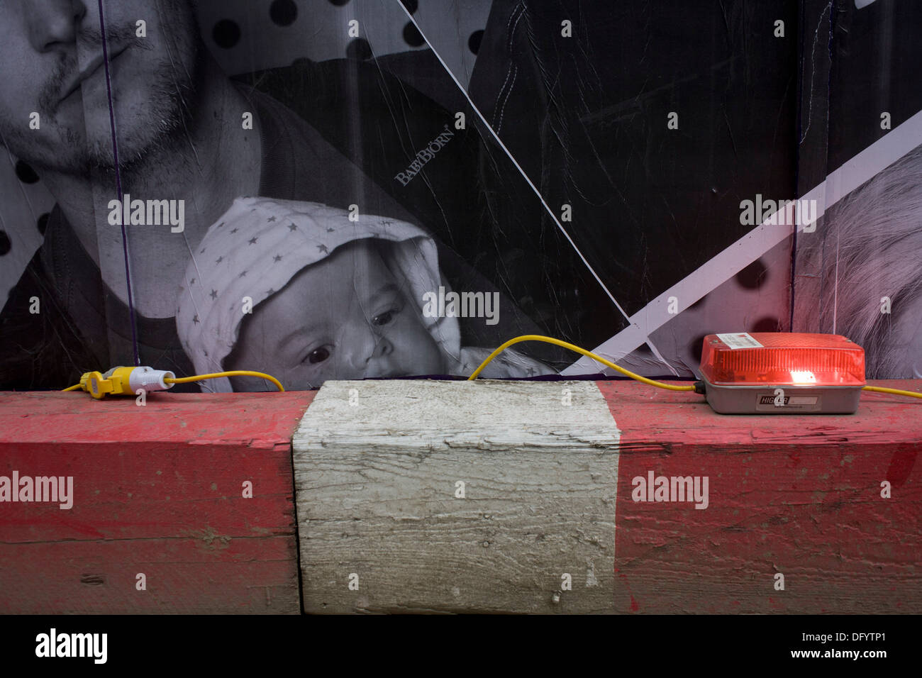A baby's face on a construction site hoarding peers over the top of a ...