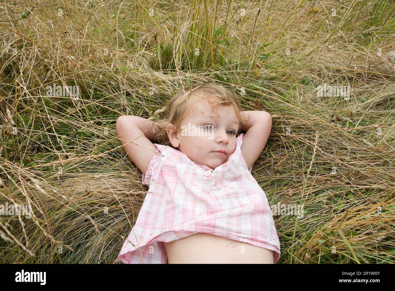 Cute Toddler Girl Laying in grass Stock Photo - Alamy