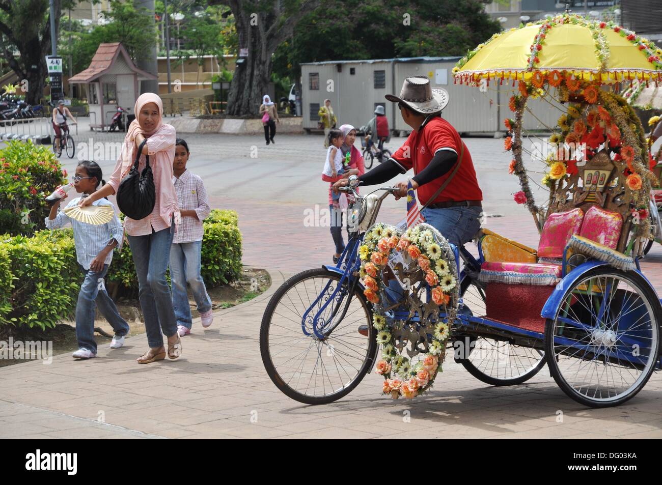 Malacca (Malaysia): a rickshaw driver offering his service to a family ...