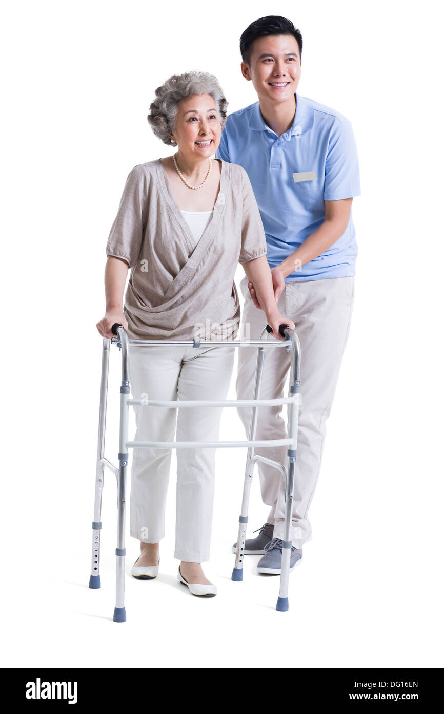 Male nursing assistant helping senior woman with walking frame Stock ...