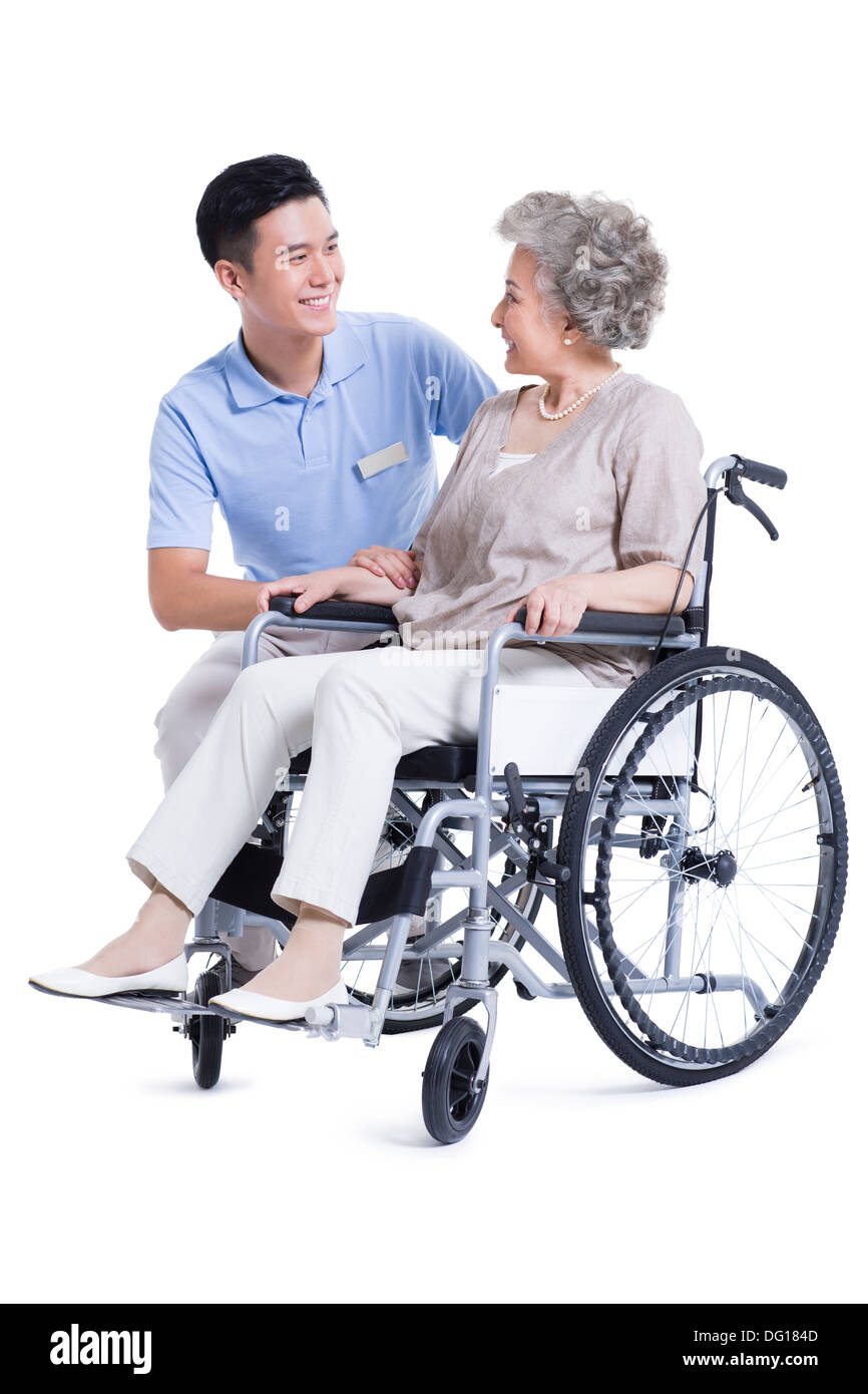 Male nursing assistant taking care of senior in wheelchair Stock Photo ...