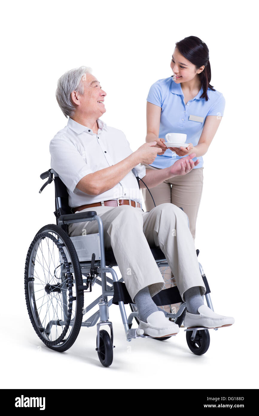 Female nursing worker serving tea to senior woman Stock Photo - Alamy
