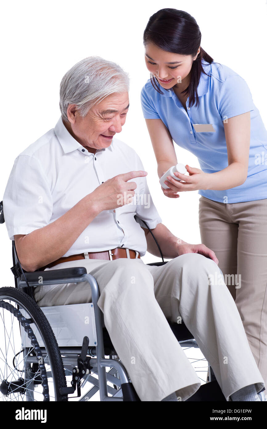 Female nursing worker showing senior man medicine Stock Photo - Alamy