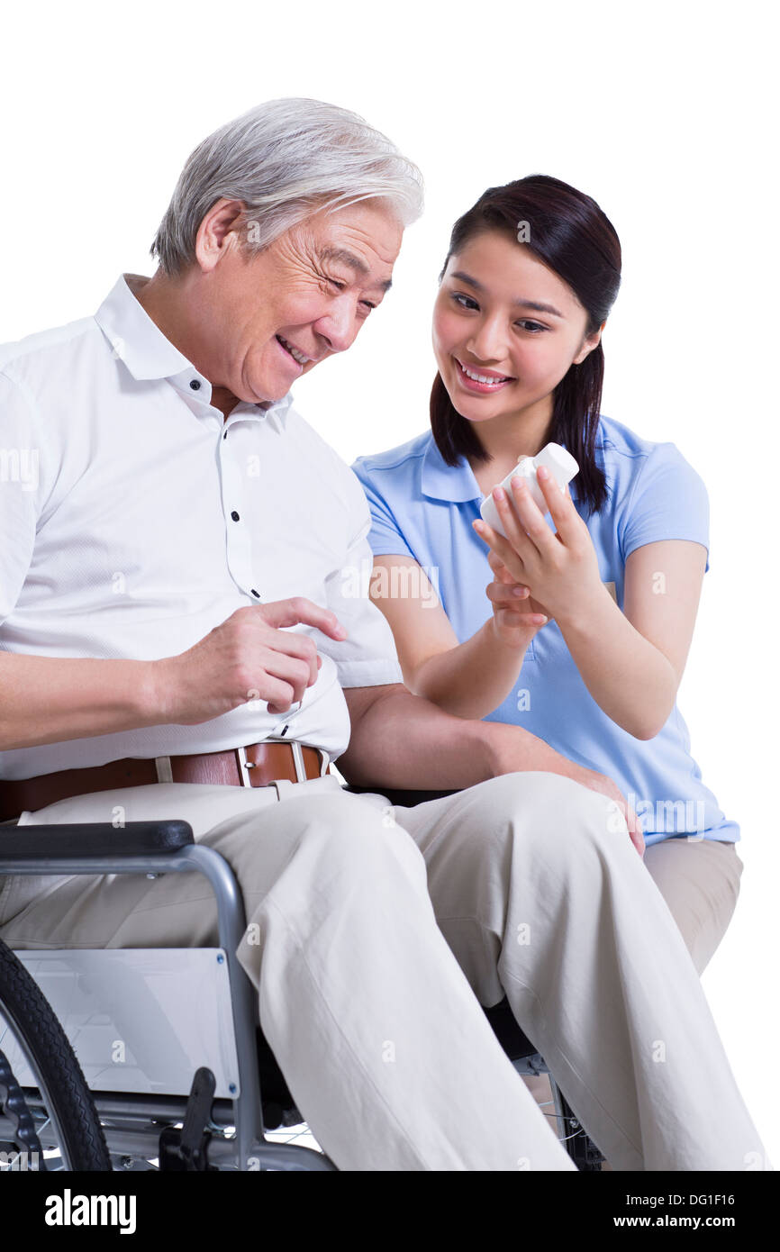 Female nursing worker showing senior man medicine Stock Photo - Alamy