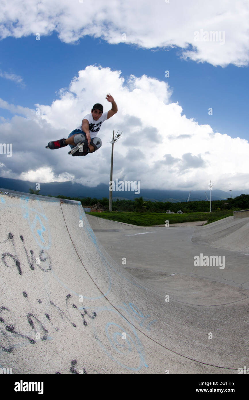 In line skate athlete performing aerial tricks in a public skate park ...