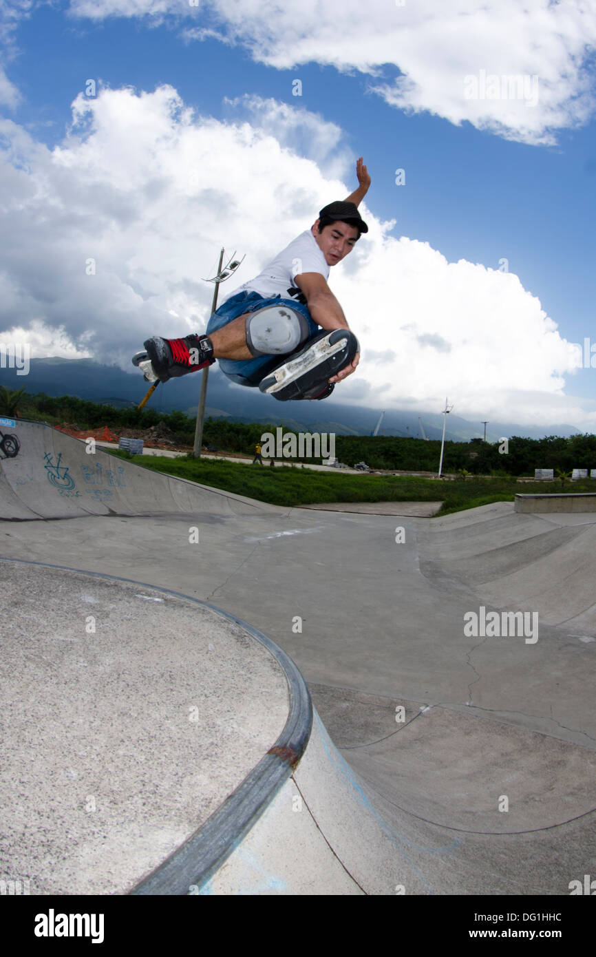 In line skate athlete performing aerial tricks in a public skate park ...