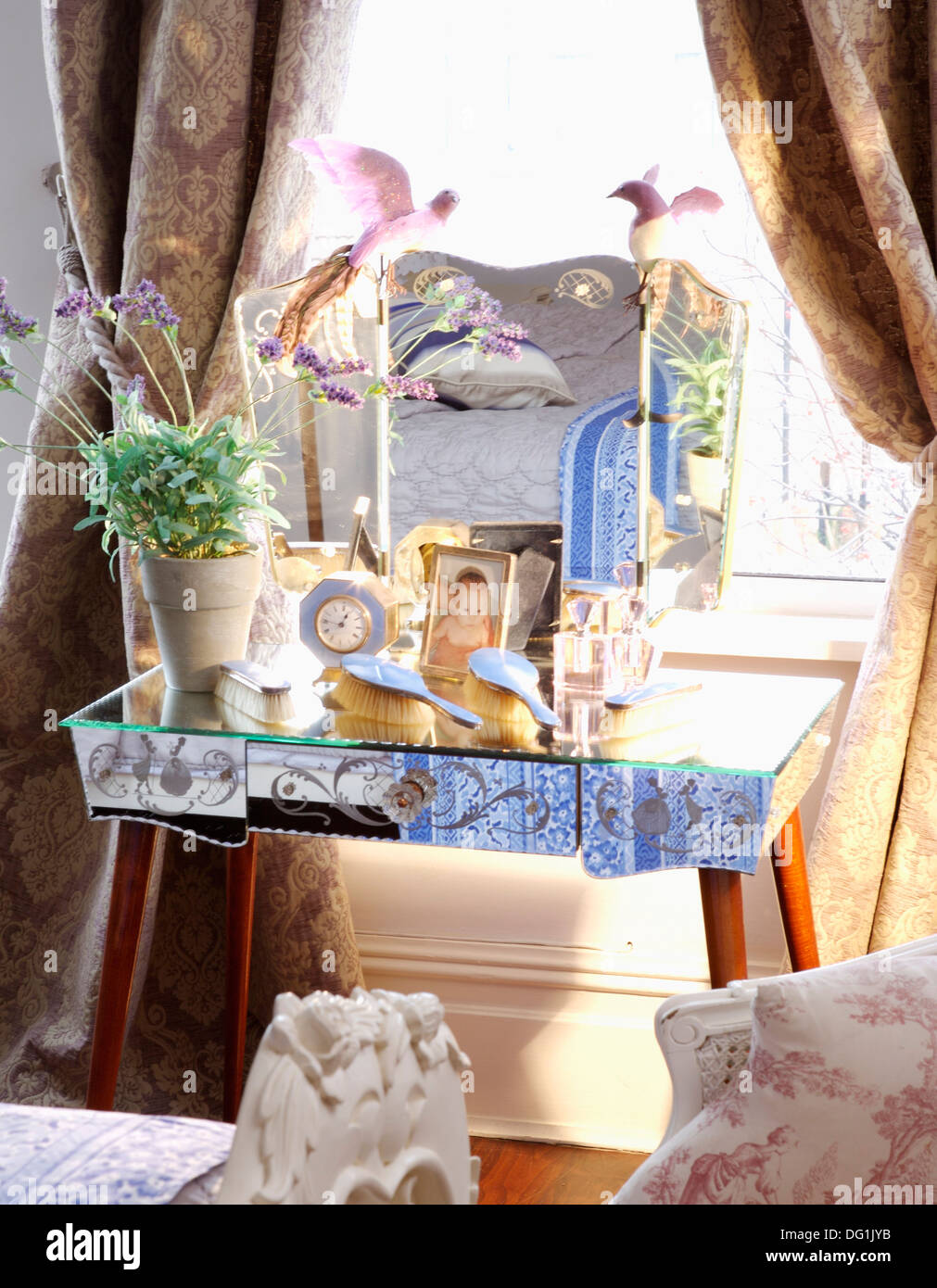 Lavender in pot beside framed photographs on mirrored dressing table ...