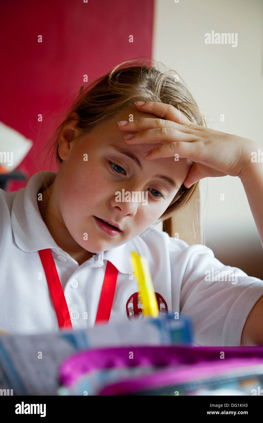 Twelve year old caucasian girl in school uniform doing school homework ...