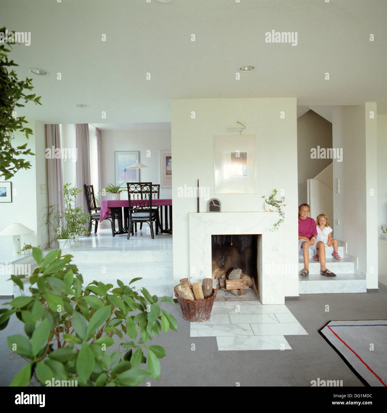 Small girl and boy sitting on steps in modern living room Stock Photo ...