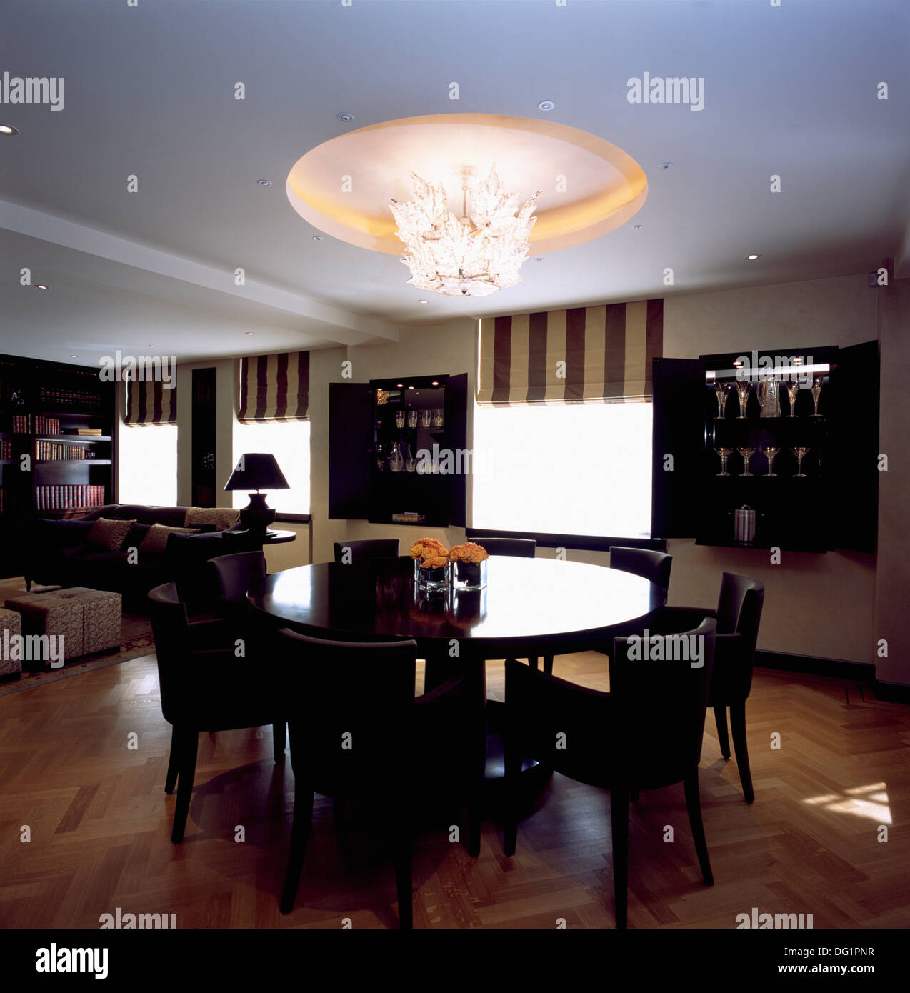 Light fitting in circular recess in ceiling above dark wood table and ...