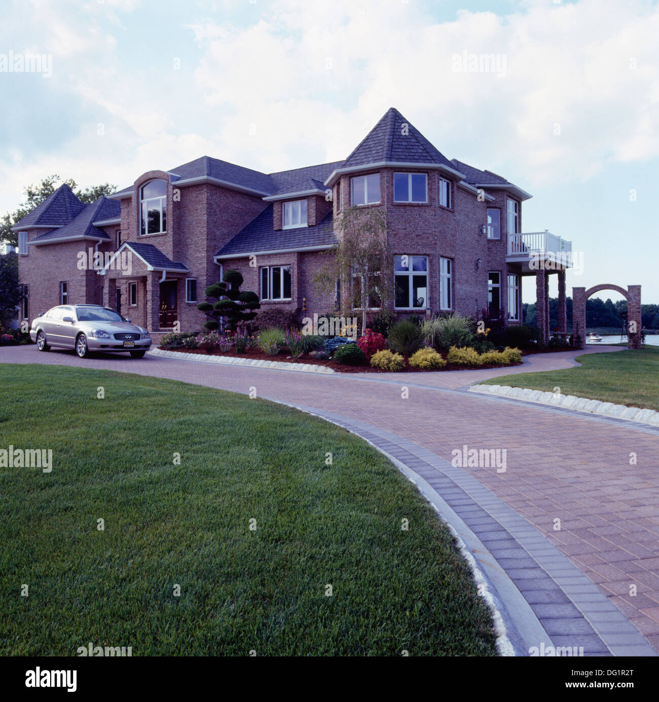 Car on paved drive in front of large new-build country house in the ...